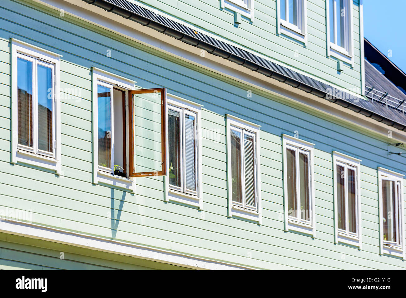 One open and several closed windows on a wooden apartment building ...