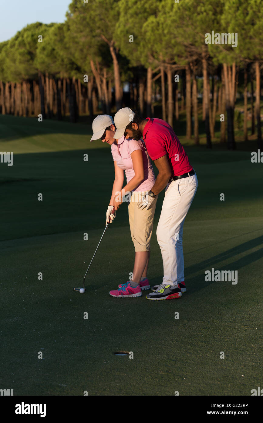 male golf instructor teaching female golf player, personal trainer ...
