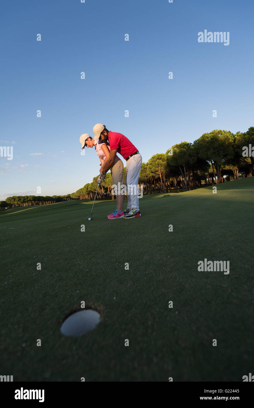 male golf instructor teaching female golf player, personal trainer ...