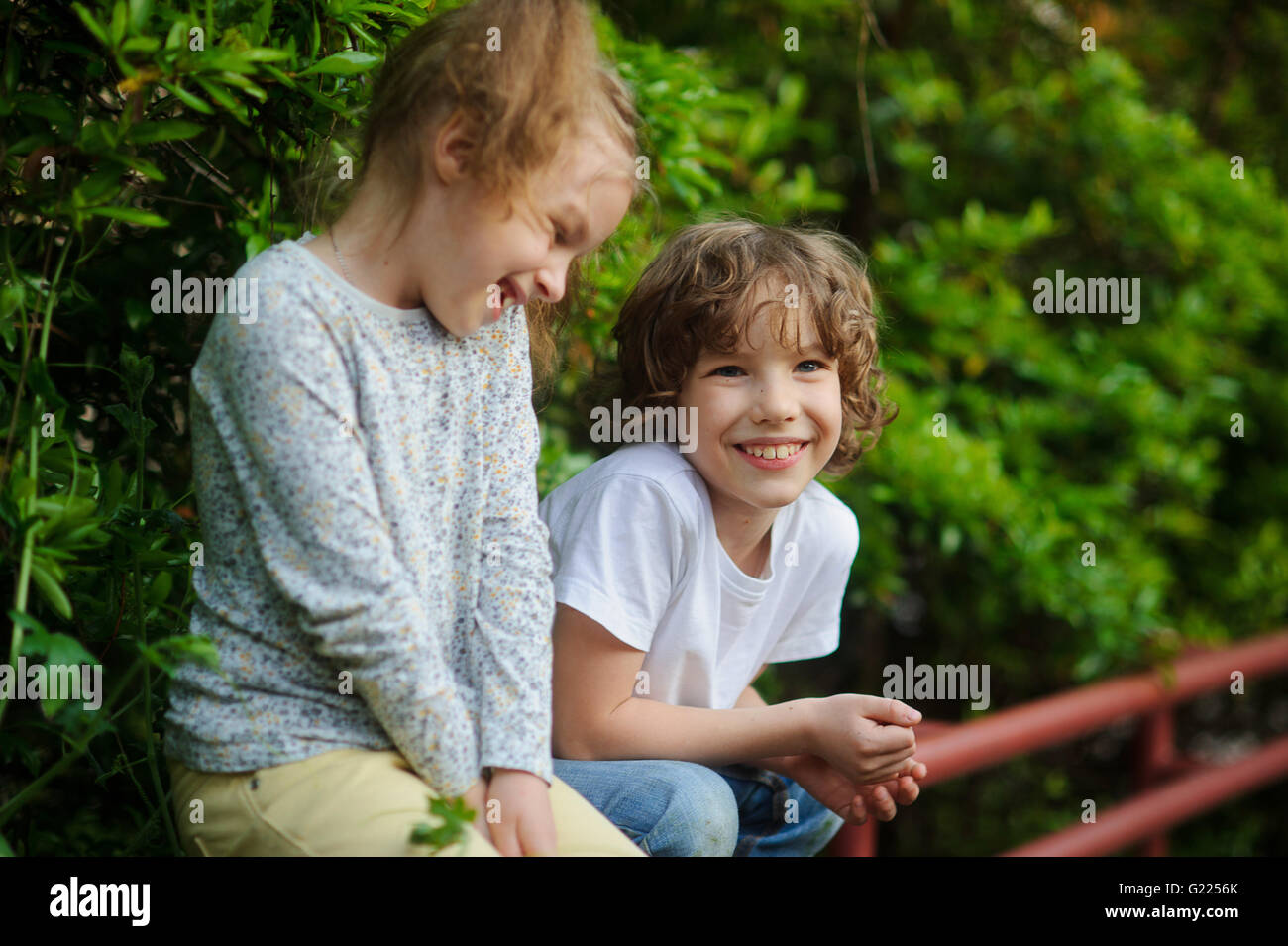 Two children sit on a fenced in park Stock Photo - Alamy