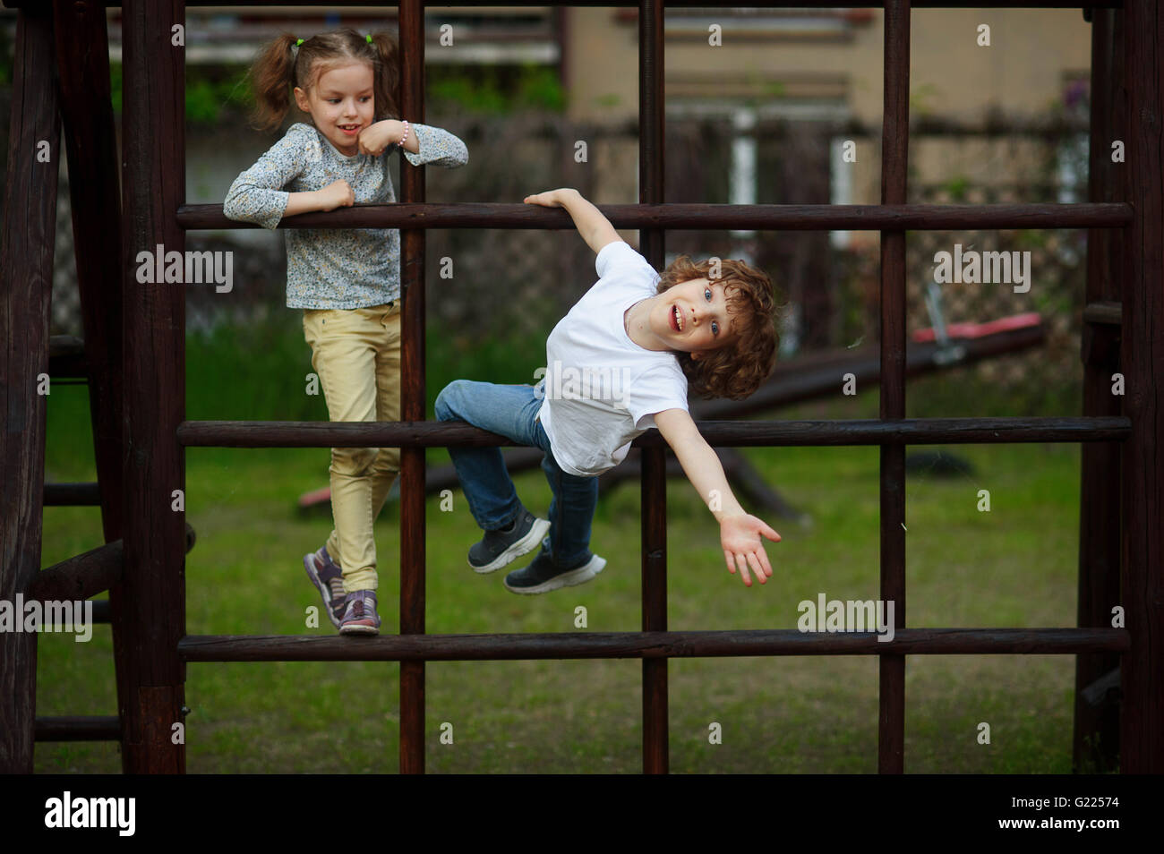 Boy and girl climb on the bars at the playground Stock Photo - Alamy