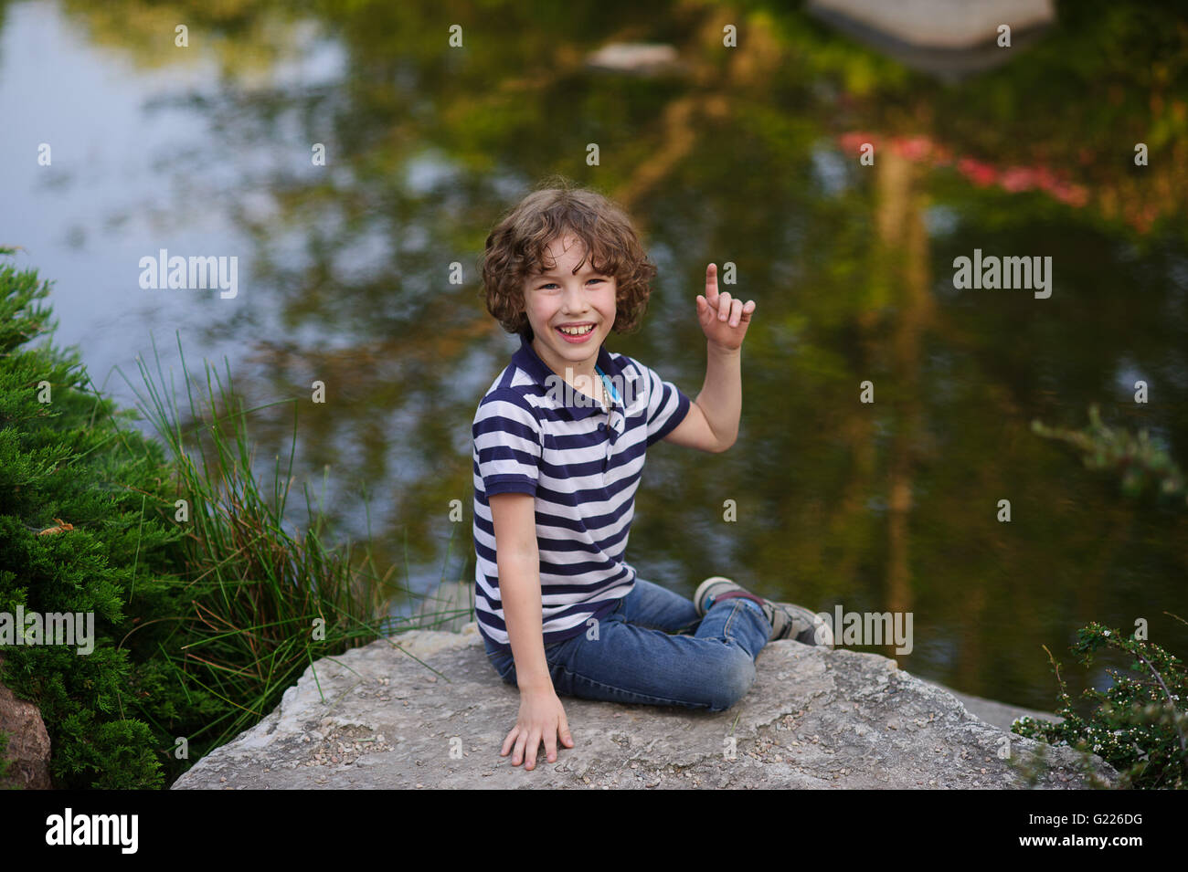 Boy sitting on a boulder near the water Stock Photo - Alamy