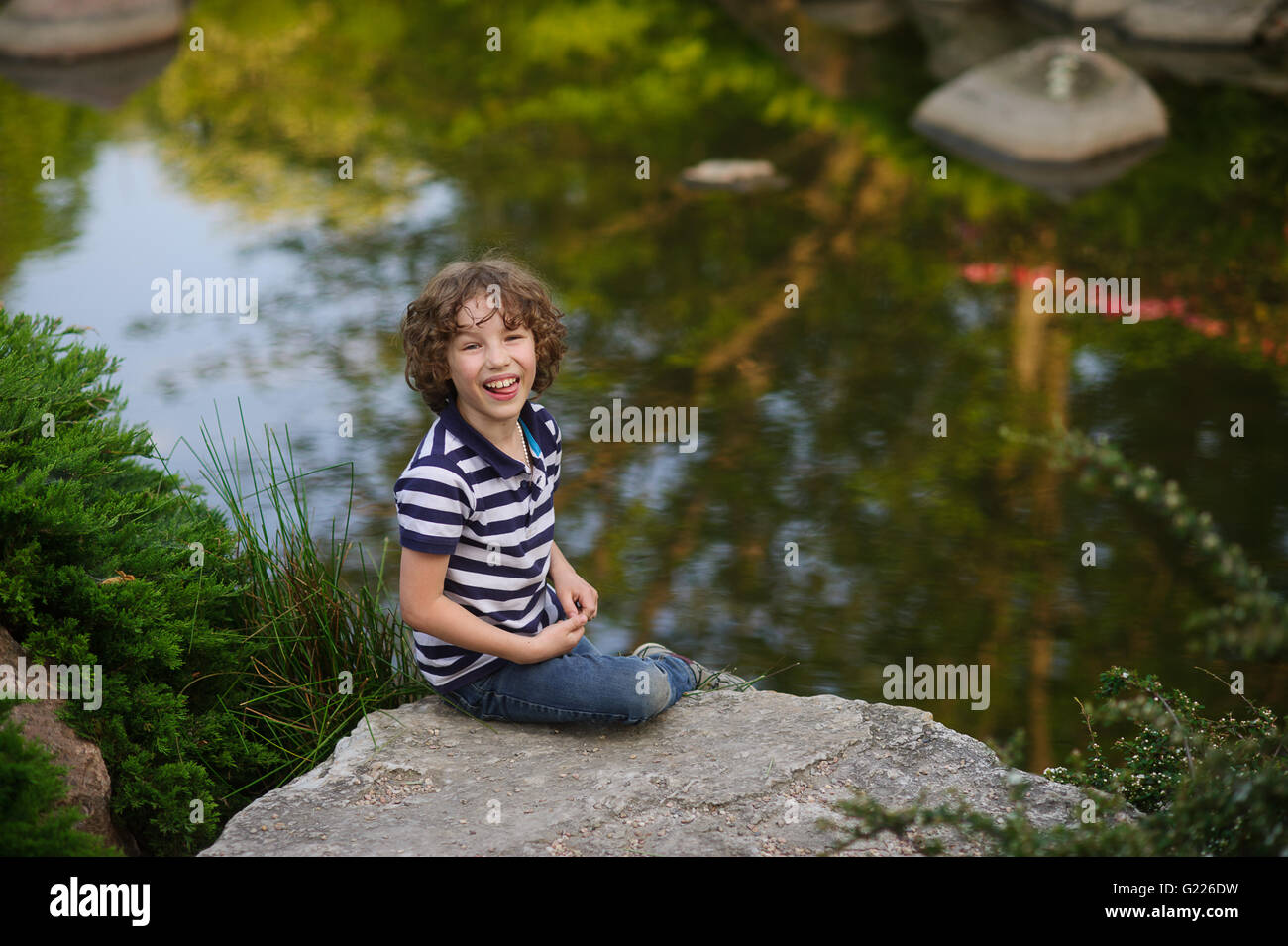 Boy sitting on a boulder in the small pond Stock Photo - Alamy