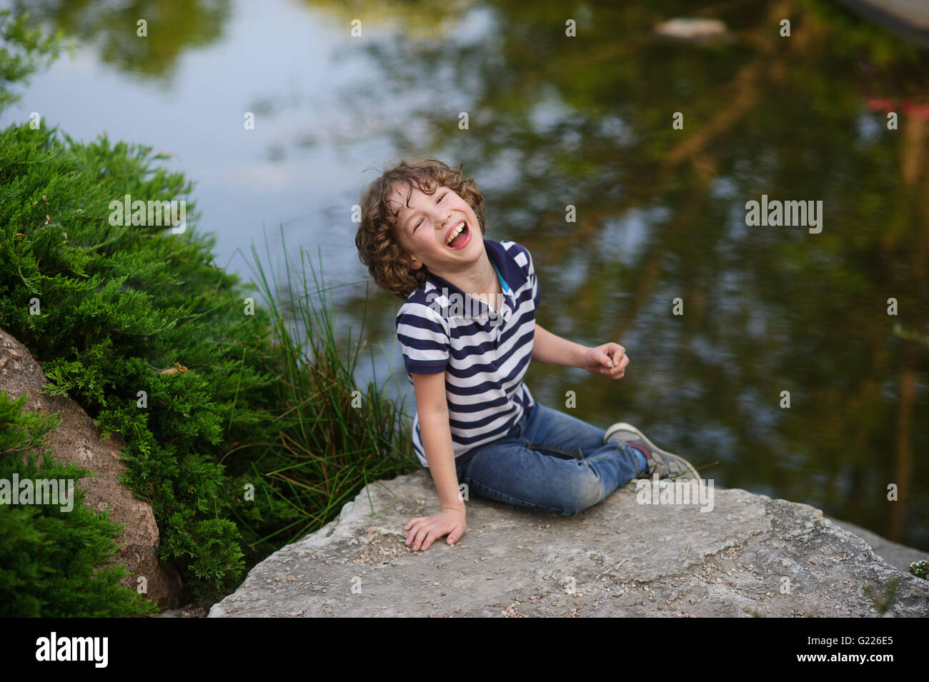 Boy sitting on the boulder in a pond Stock Photo - Alamy