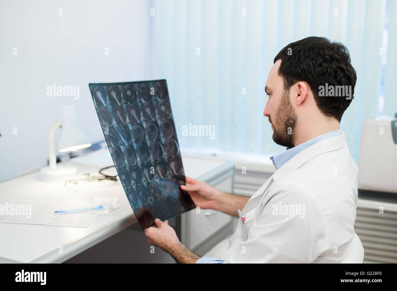 Young male physician reading and reviewing a MRI brain scan Stock Photo ...