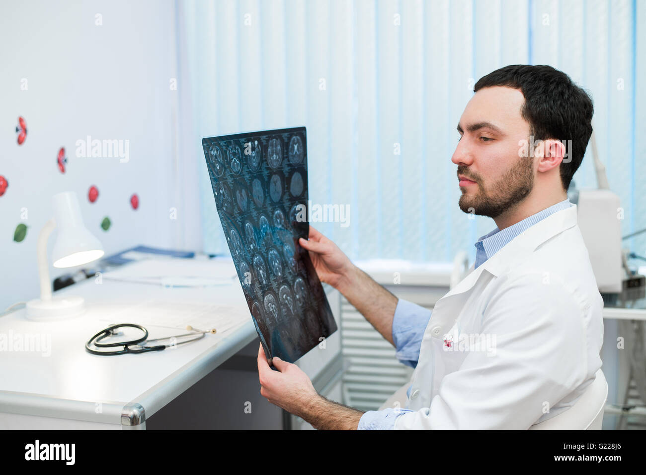 Portrait of a handsome caucasian male radiologist holding x-ray while ...