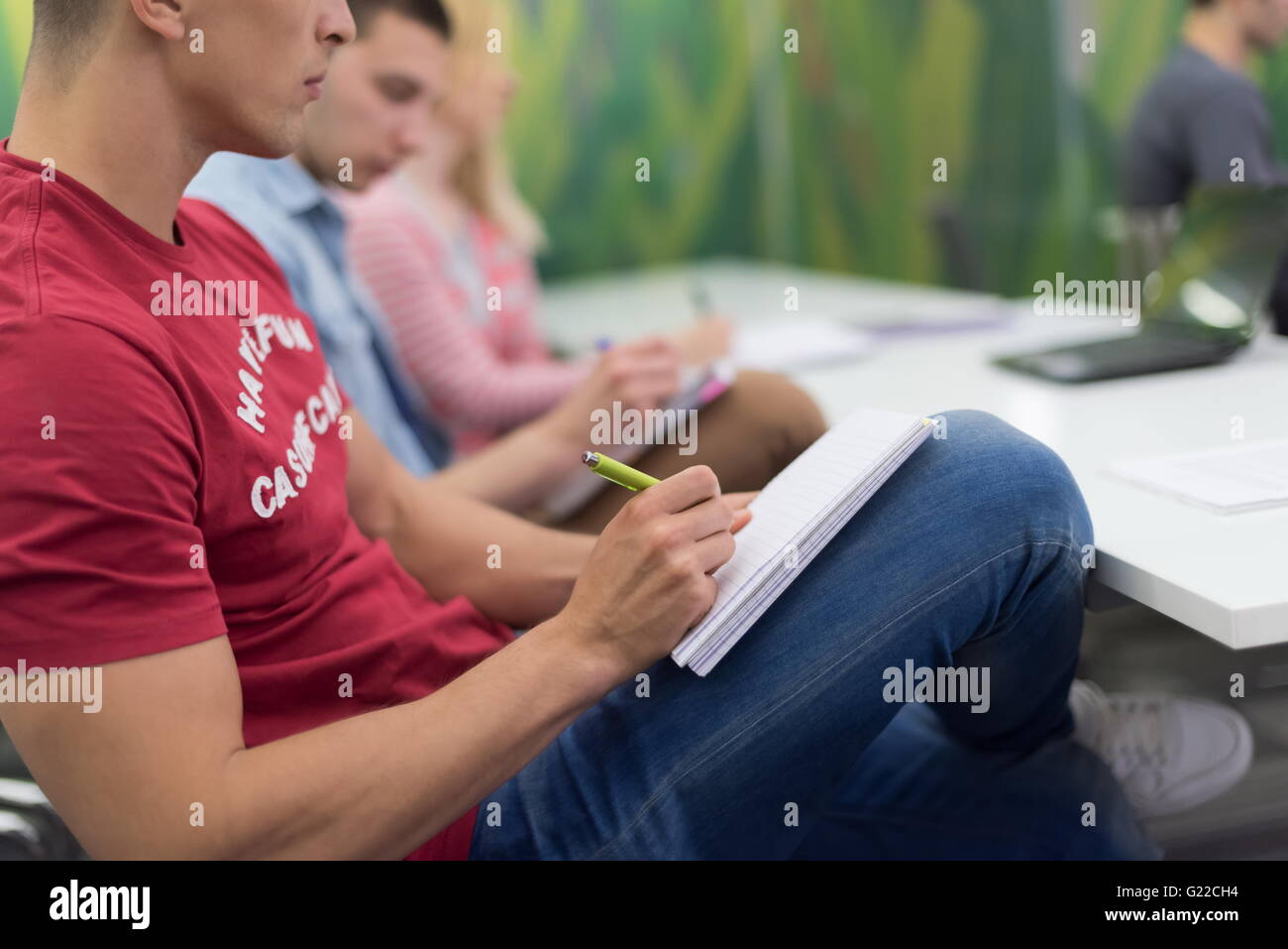 male student taking notes in classroom. business education concept ...