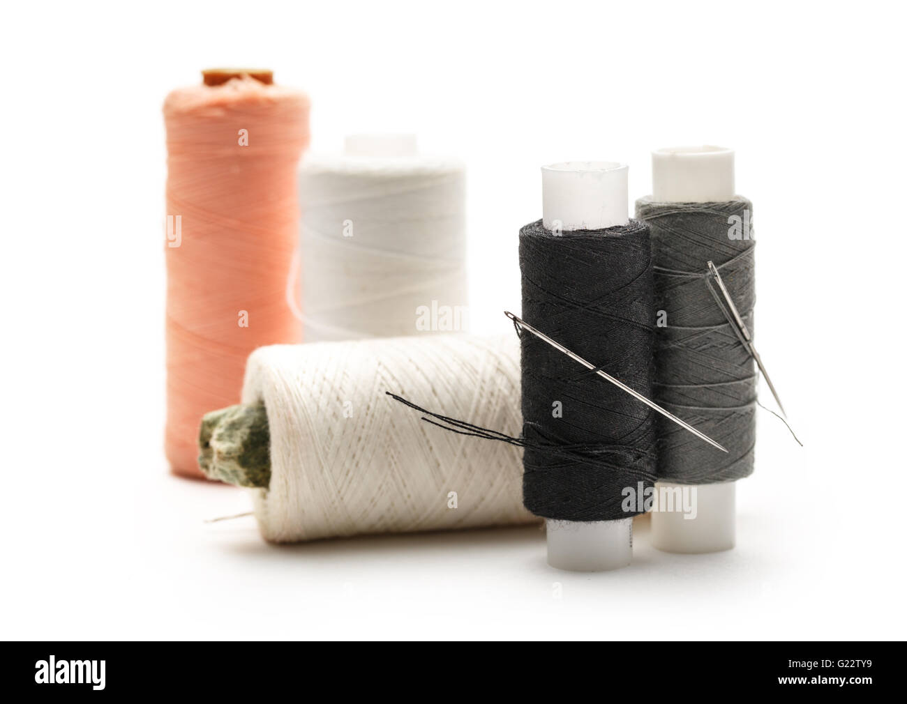 Thread bobbins and needles on white background Stock Photo - Alamy