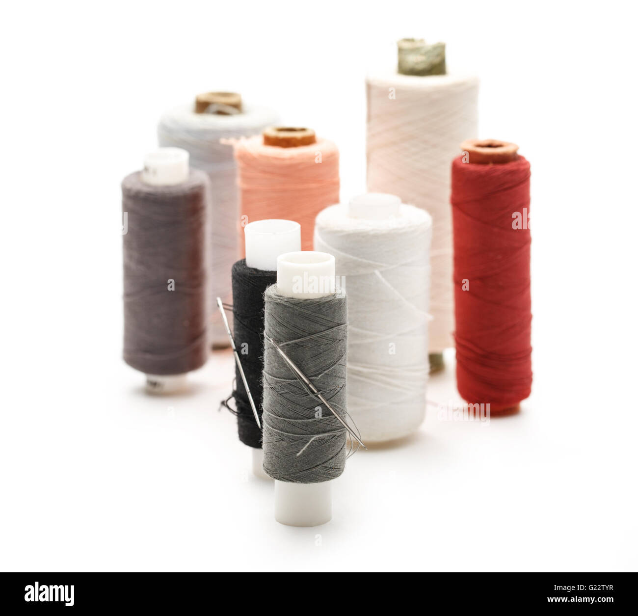 Thread bobbins and needles on white background Stock Photo - Alamy