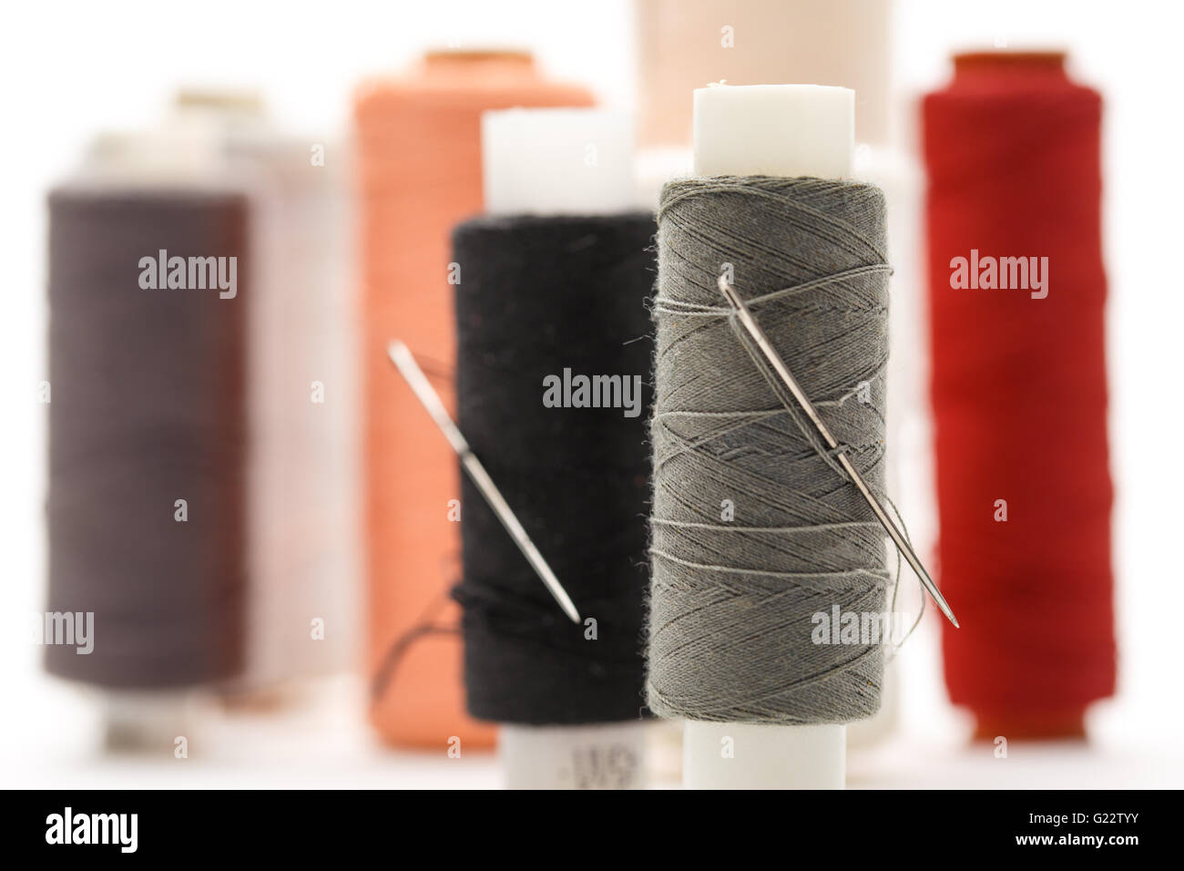 Thread bobbins and needles on white background Stock Photo - Alamy