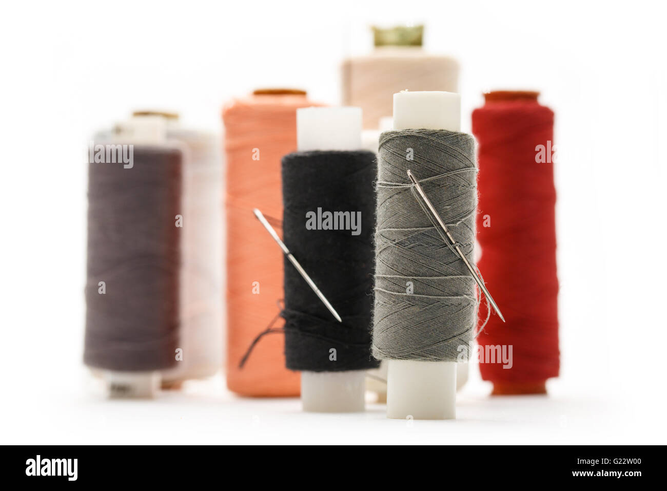 Thread bobbins and needles on white background Stock Photo - Alamy
