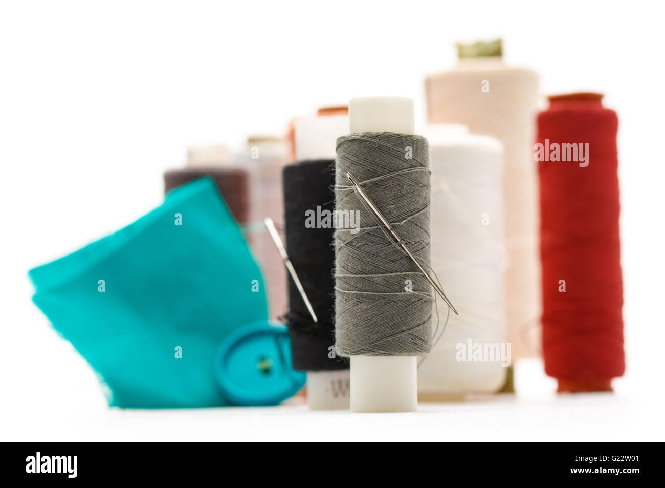 Thread bobbins and needles on white background Stock Photo - Alamy