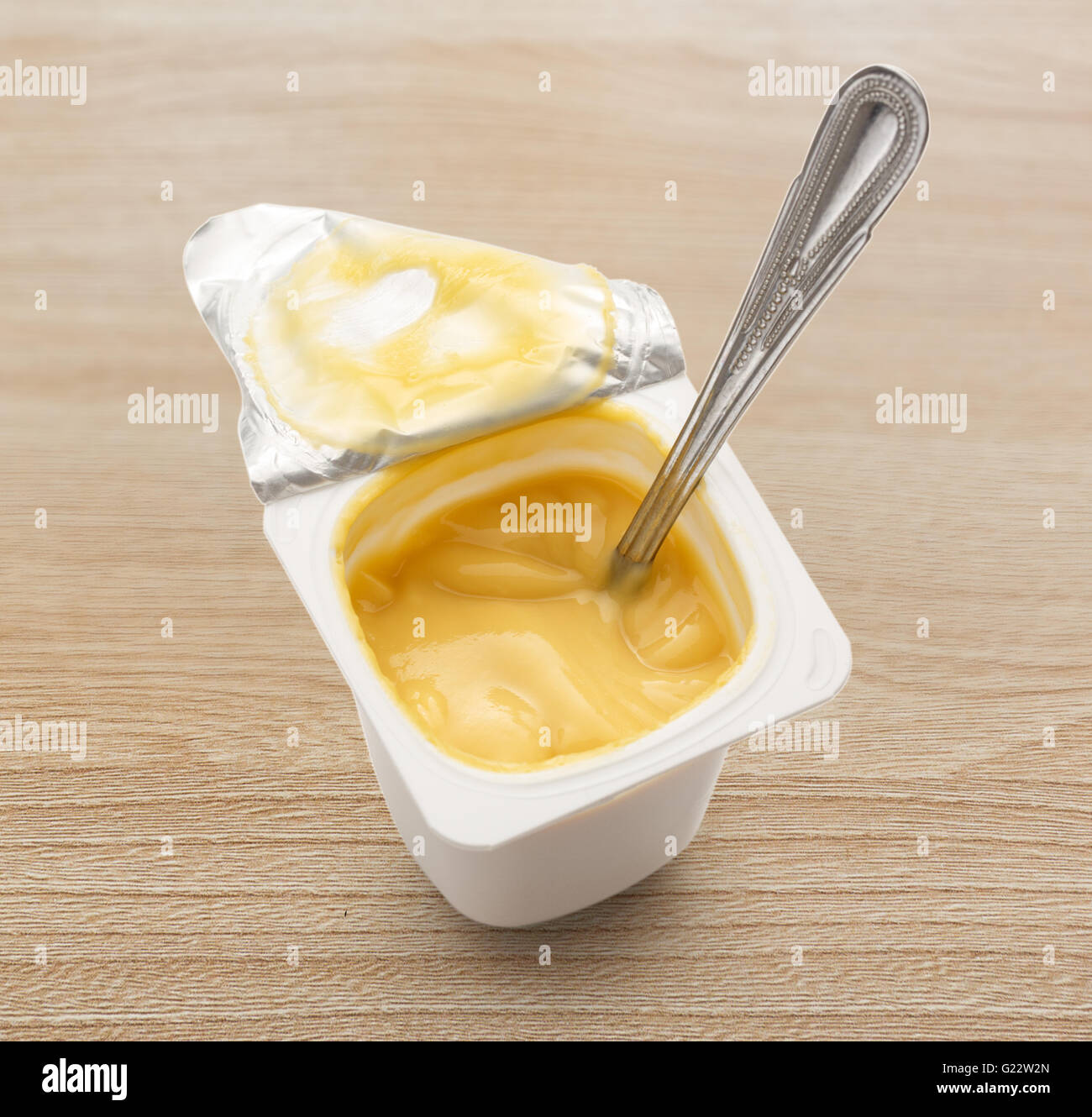 Open yogurt in pot with metal spoon closeup Stock Photo - Alamy