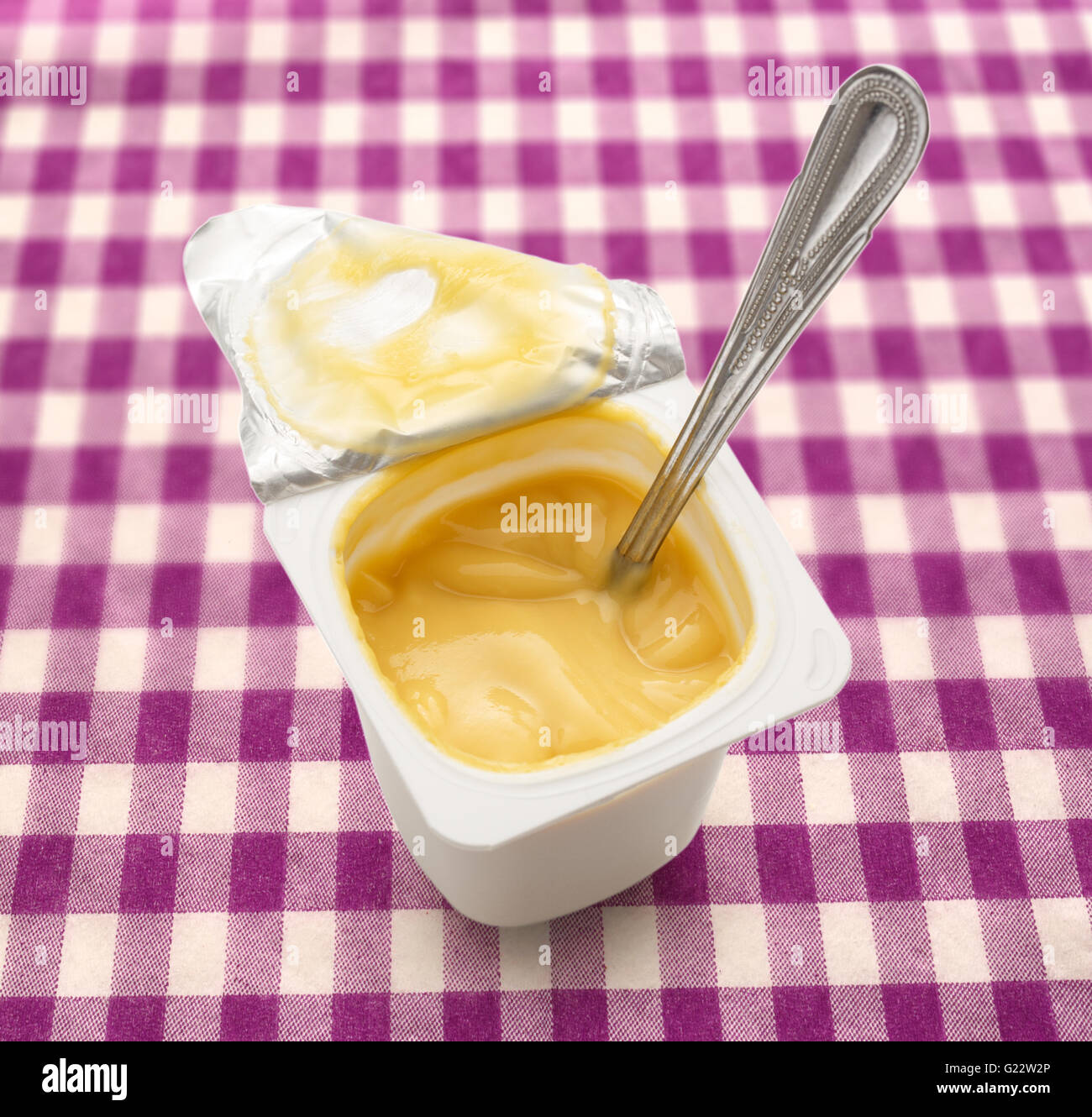 Open yogurt in pot with metal spoon closeup Stock Photo - Alamy