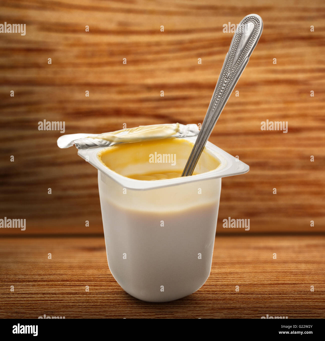 Open yogurt in pot with metal spoon closeup Stock Photo - Alamy