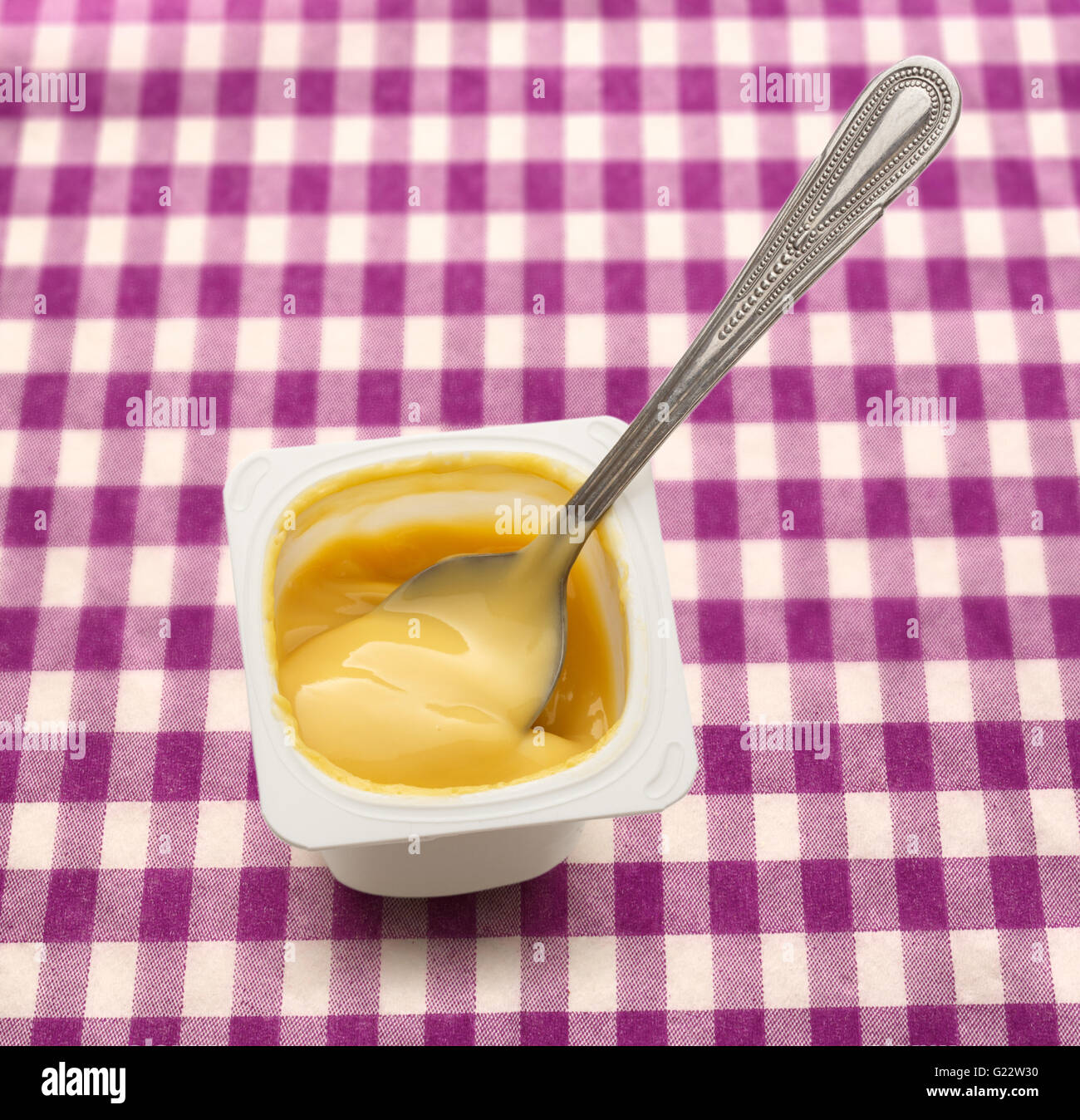 Open yogurt in pot with metal spoon closeup Stock Photo - Alamy