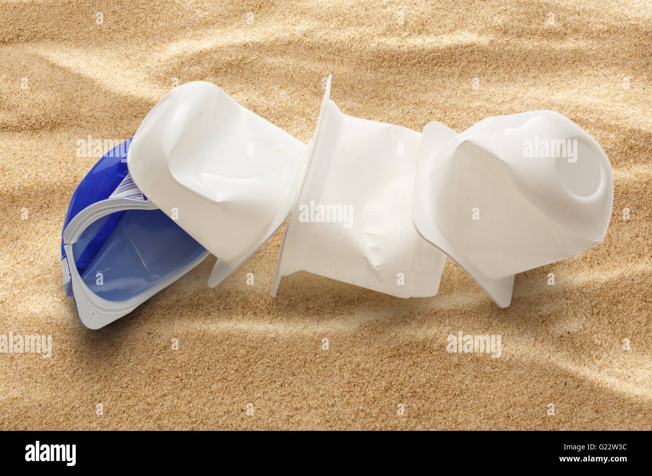 Empty crushed plastic yogurt pots on sand Stock Photo - Alamy