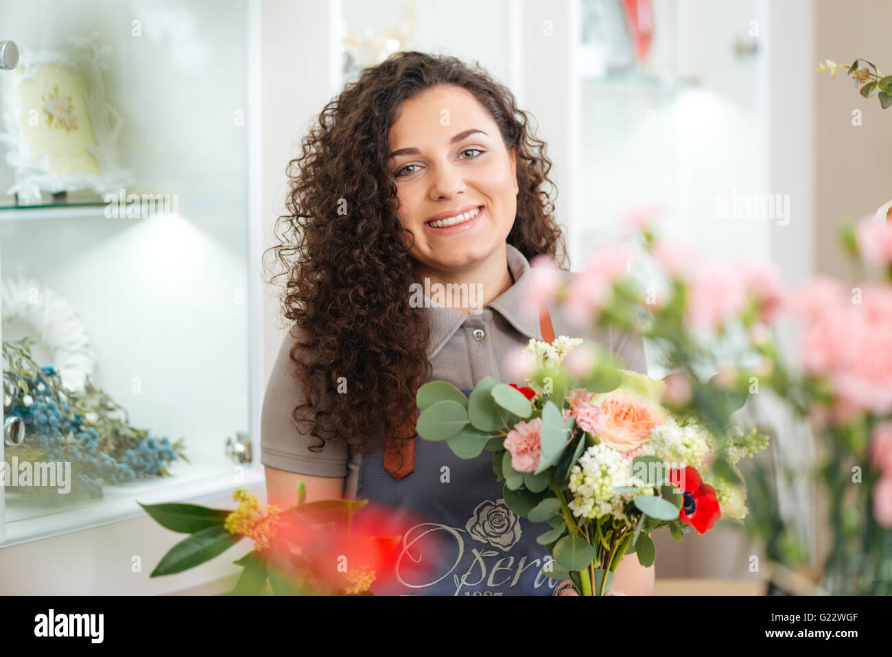 Cheerful beautiful young woman florist at work in flower shop Stock ...