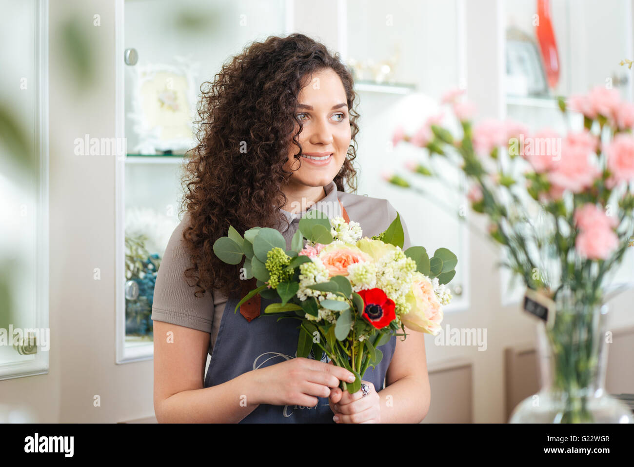 Happy cute young woman florist working in flower shop Stock Photo - Alamy