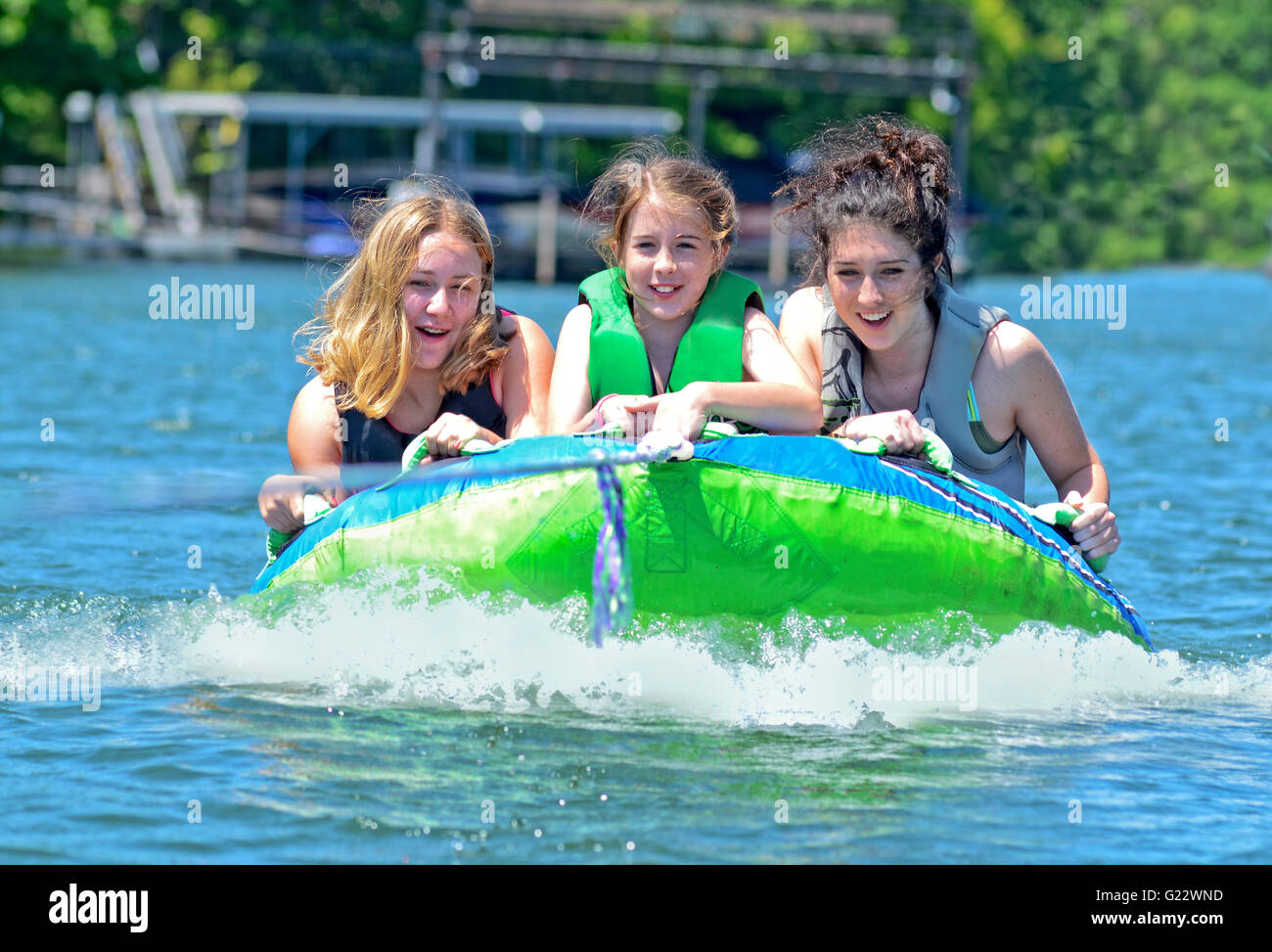 Three teen girls on a tube behind a boat Stock Photo - Alamy