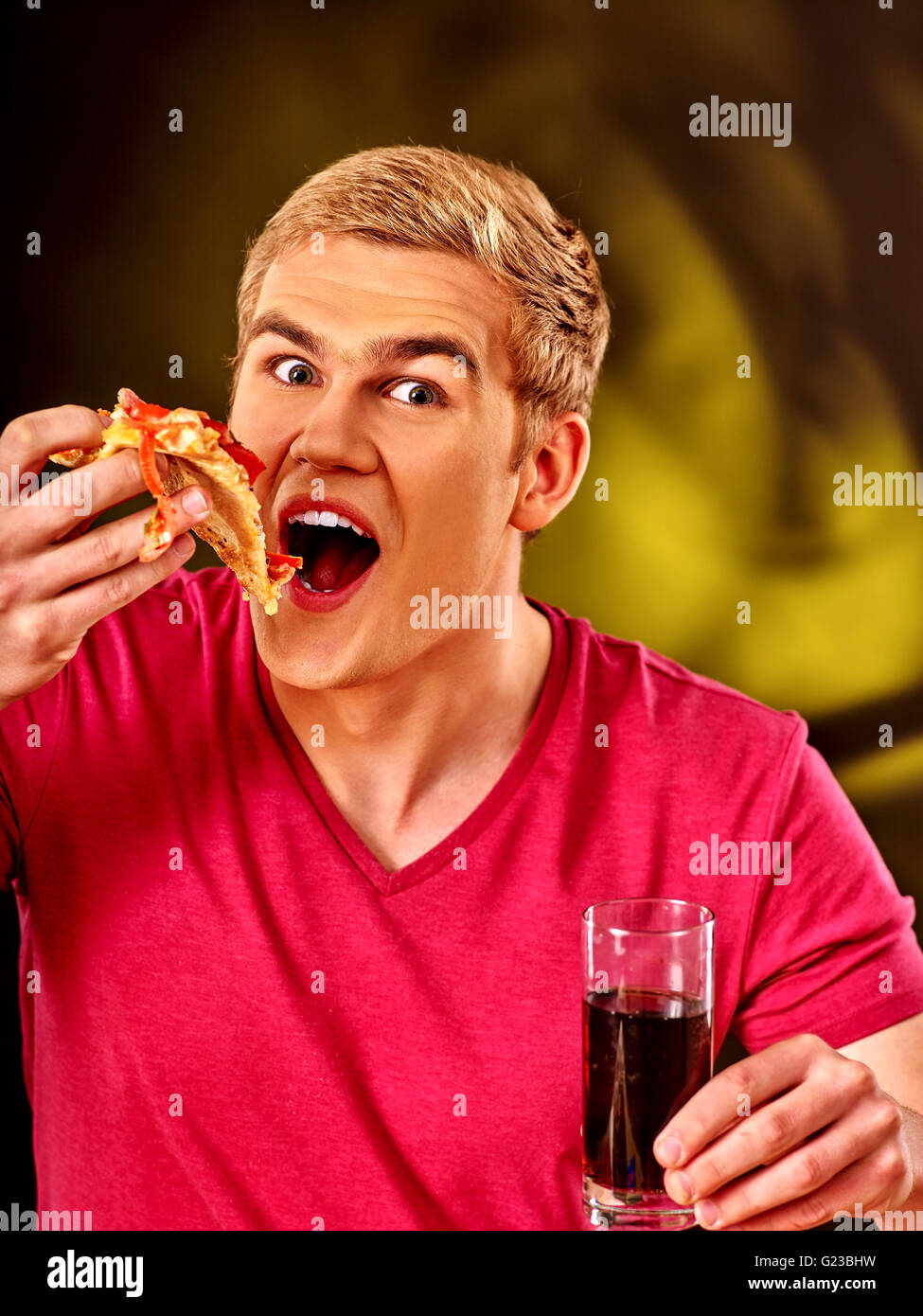 Young man eating slice of pizza Stock Photo - Alamy