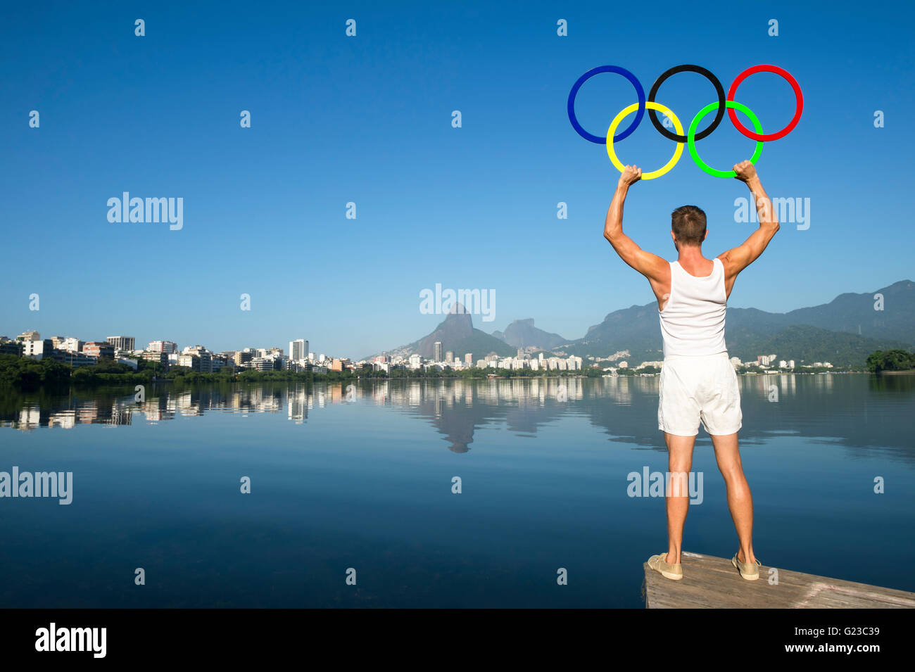 RIO DE JANEIRO - MARCH 27, 2016: Athlete holds Olympic rings above a ...