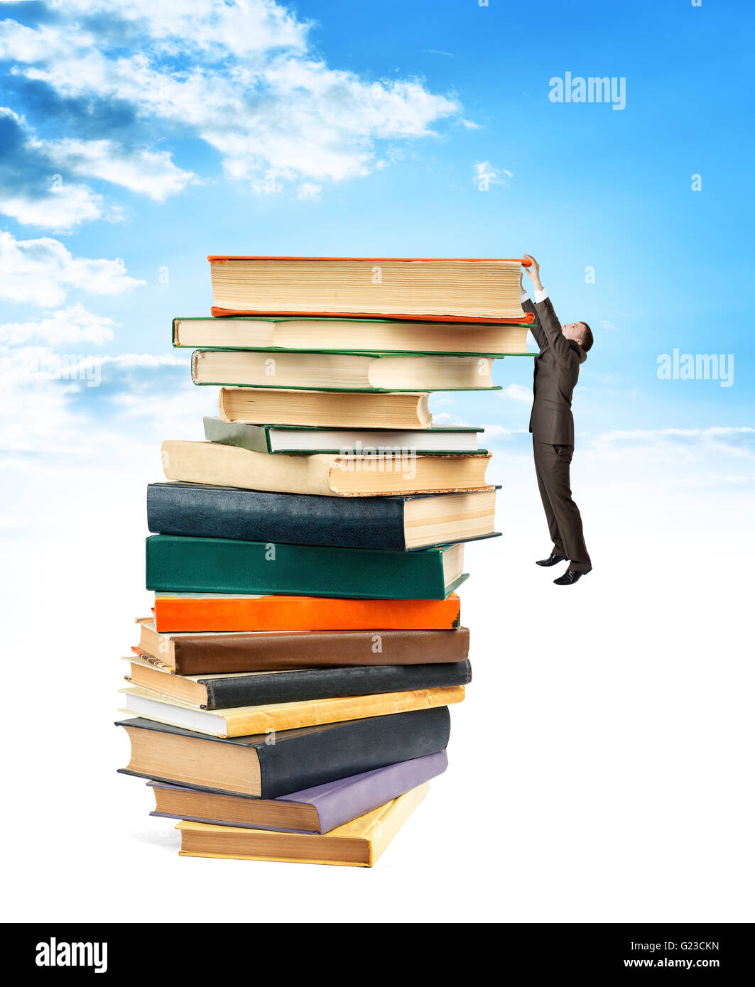 Businessman hanging on top of stack books Stock Photo - Alamy