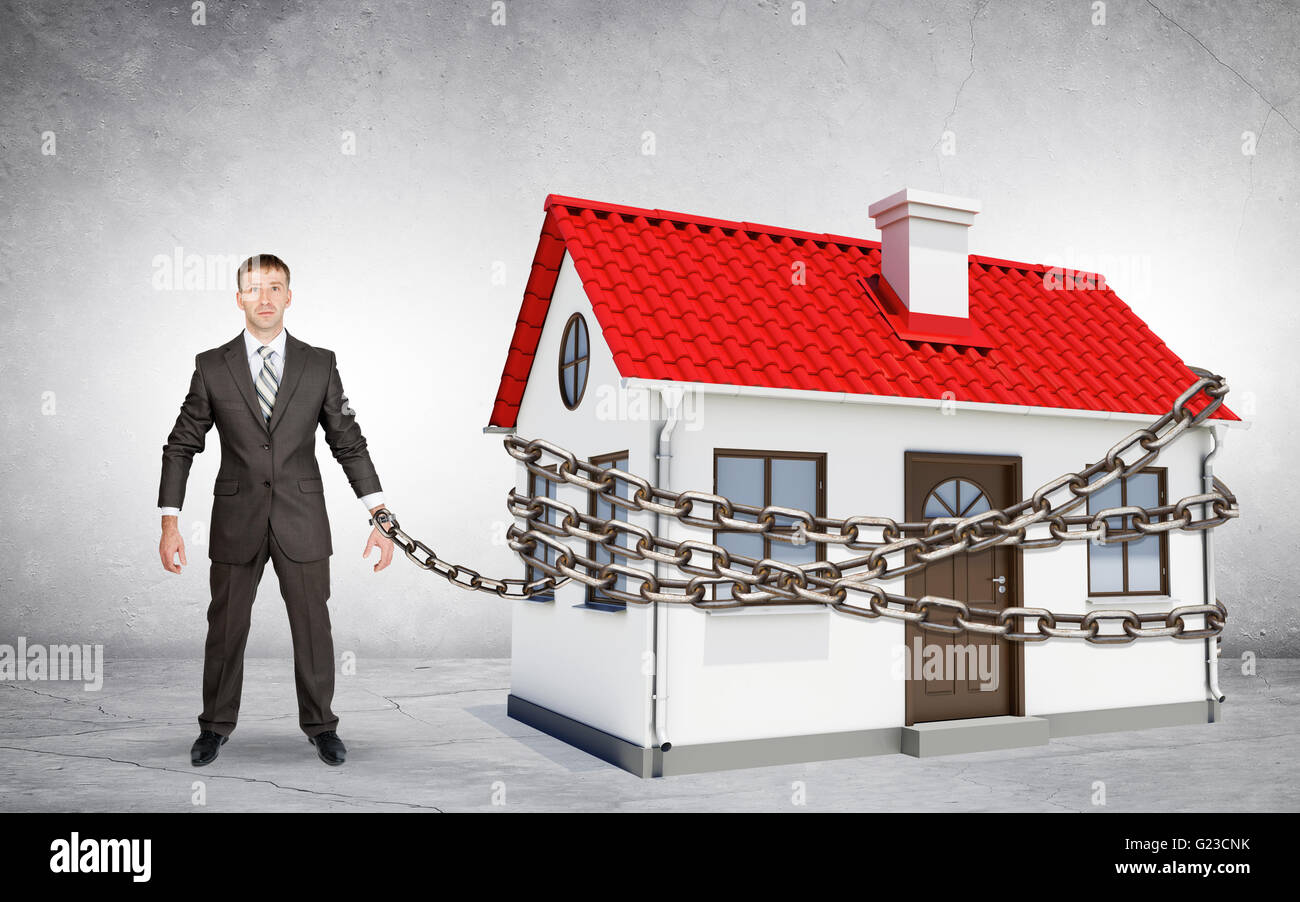 Businessman chained to house Stock Photo - Alamy