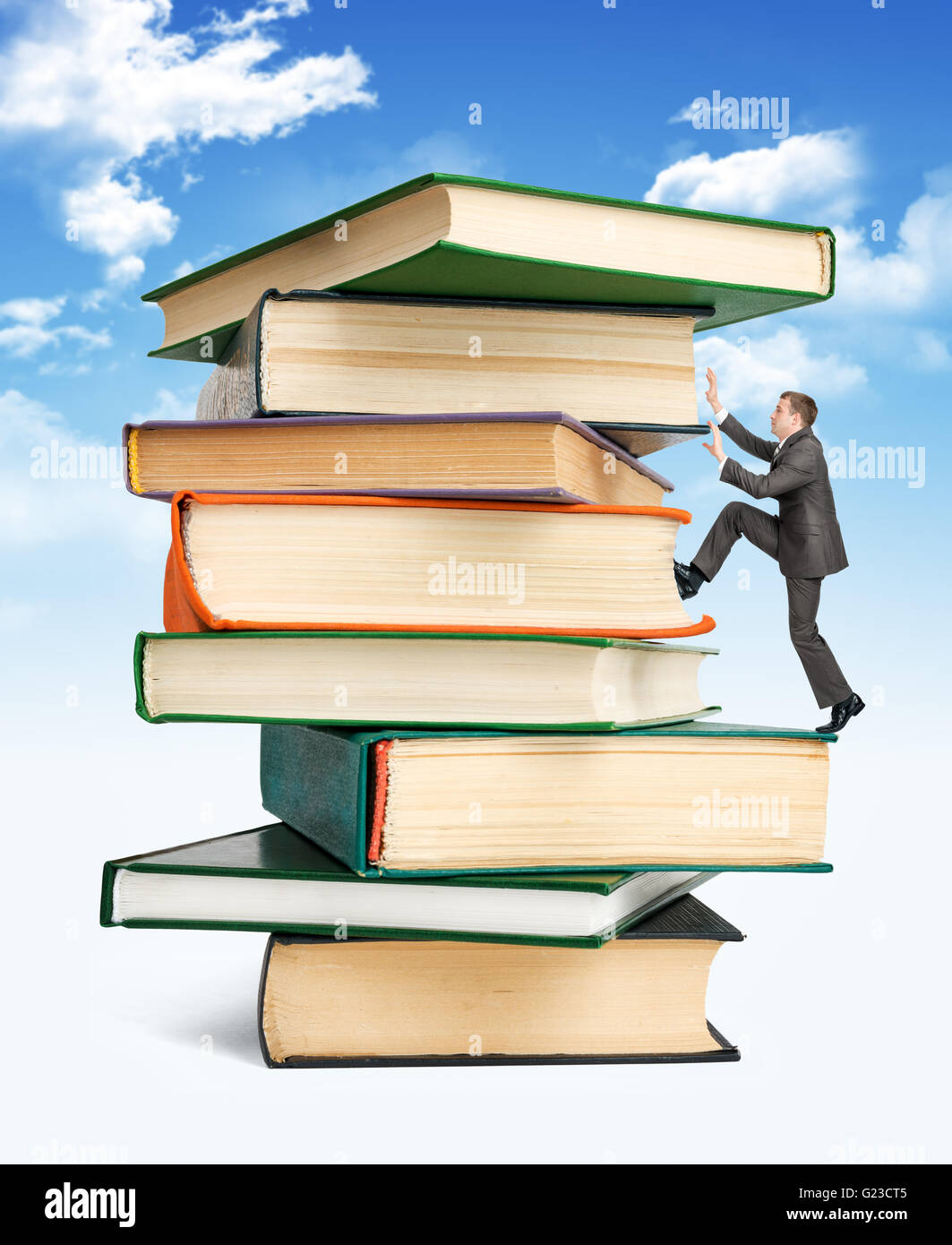 Pile of books with businessman climbing it Stock Photo - Alamy