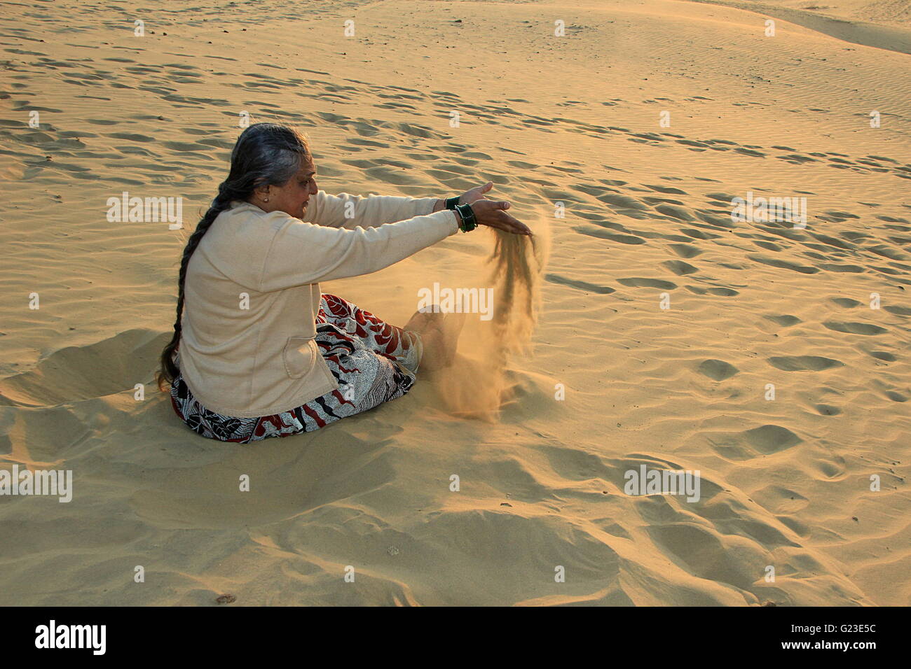 Indian lady playing with smooth and fine sand at sunset at Sam Sand ...