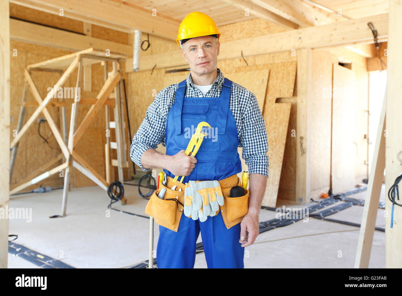 Workman with wrench inside wooden house under construction Stock Photo ...