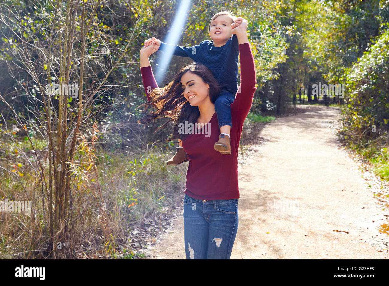 kid boy sitting on mother shoulders walking in the park trail Stock ...