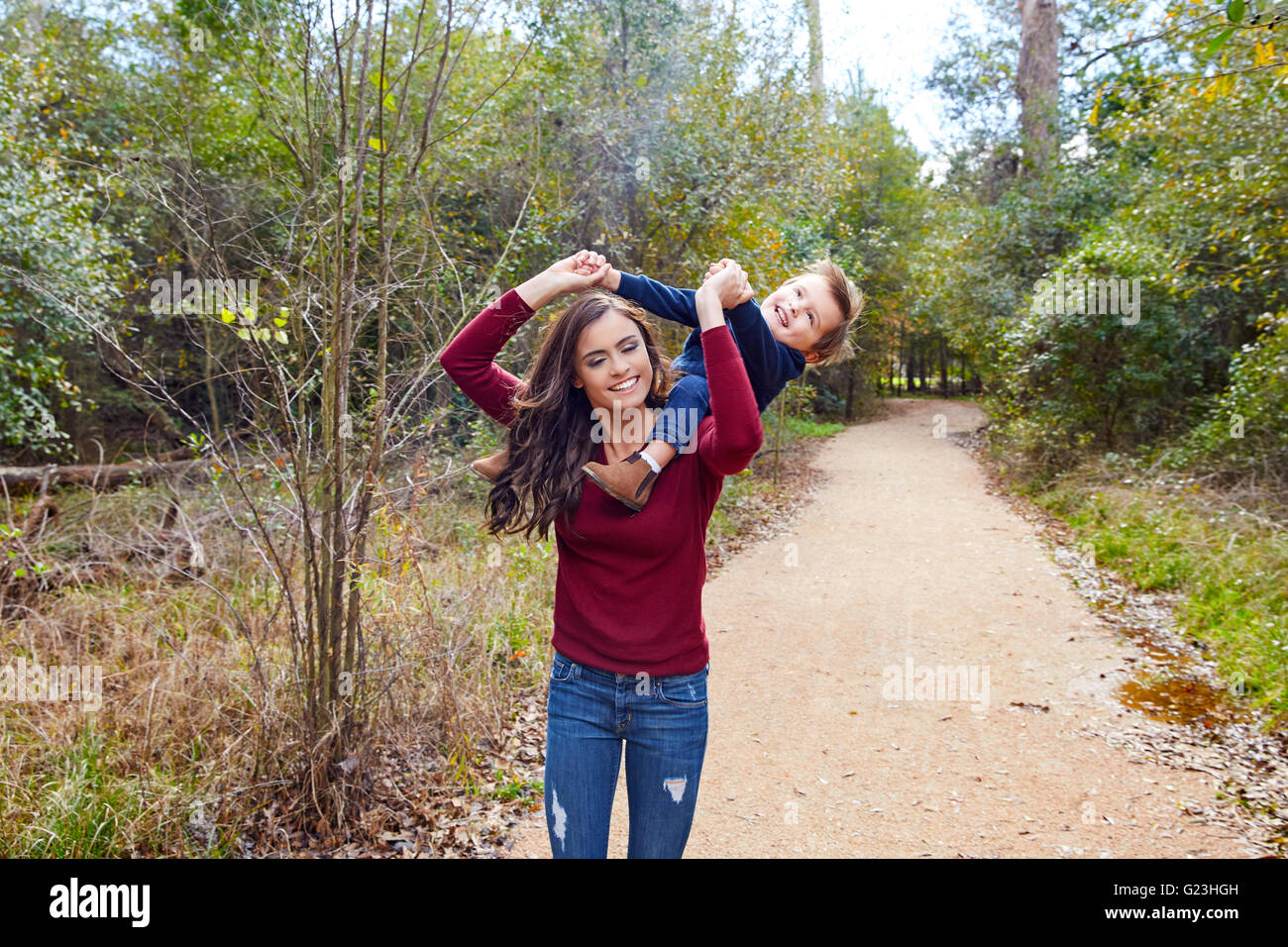 kid boy sitting on mother shoulders walking in the park trail Stock ...