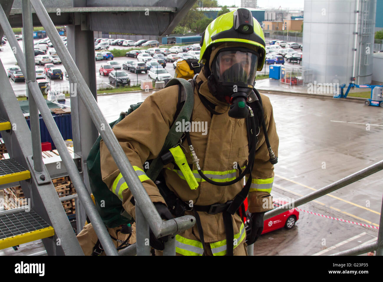 Firefighter wearing breathing apparatus ascending a metal staircase ...
