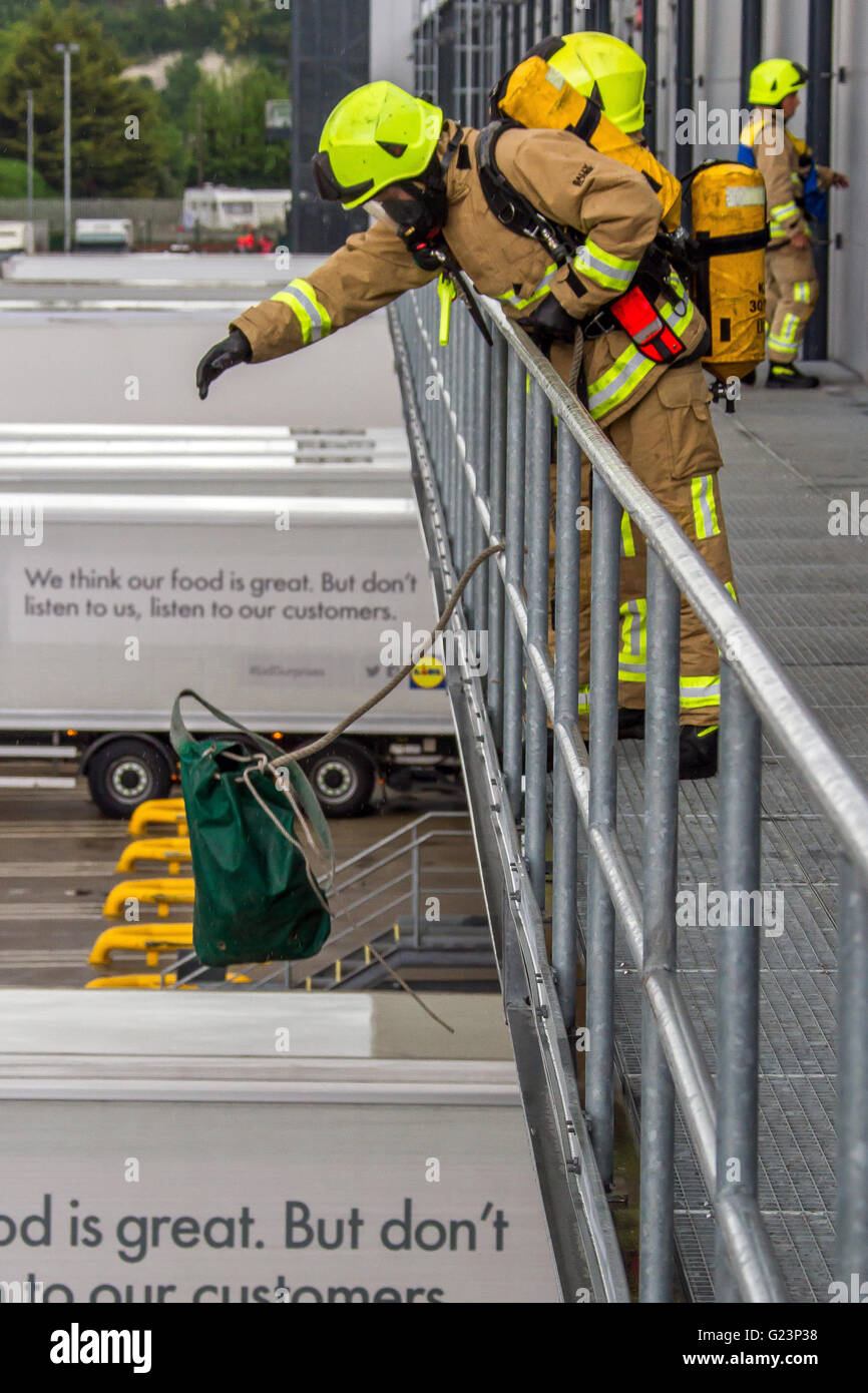 Firefighter wearing breathing apparatus throws a line from an external ...