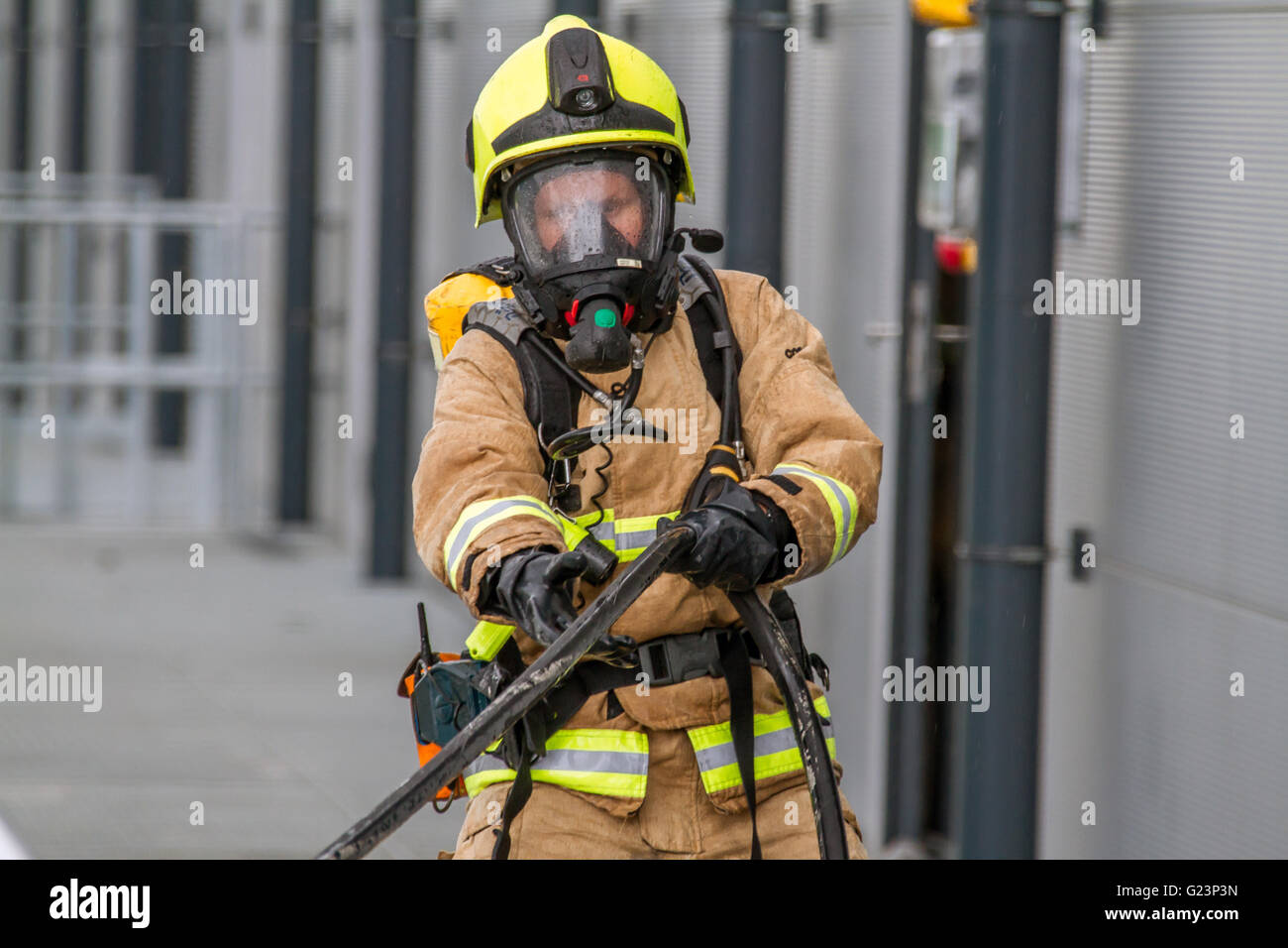 Firefighter wearing breathing apparatus drags a hosereel line on a ...