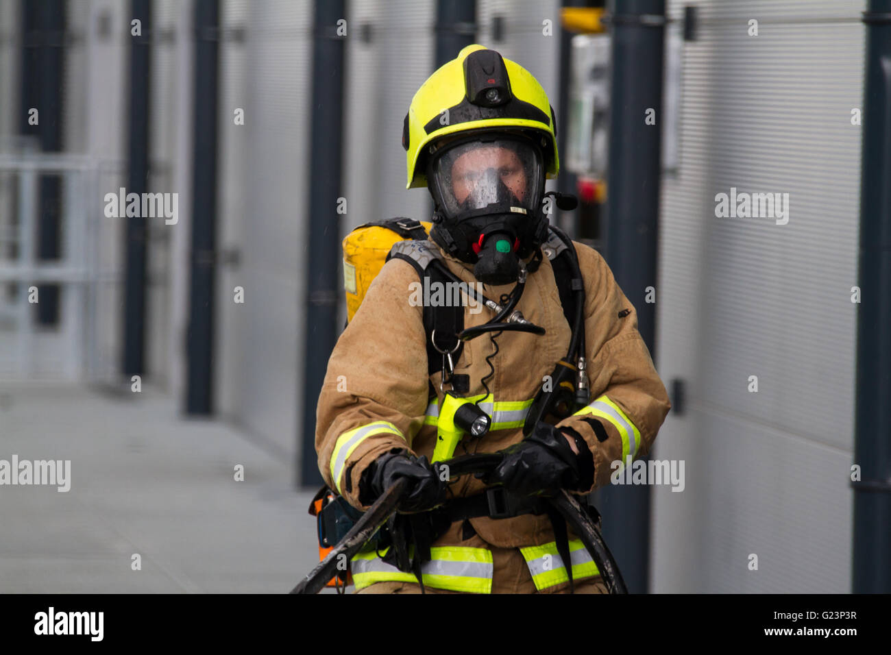 Female Firefighter wearing breathing apparatus drags a hosereel line on ...