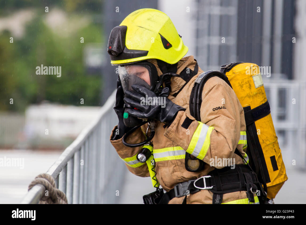 Firefighter wearing breathing apparatus drags a hosereel line on a ...