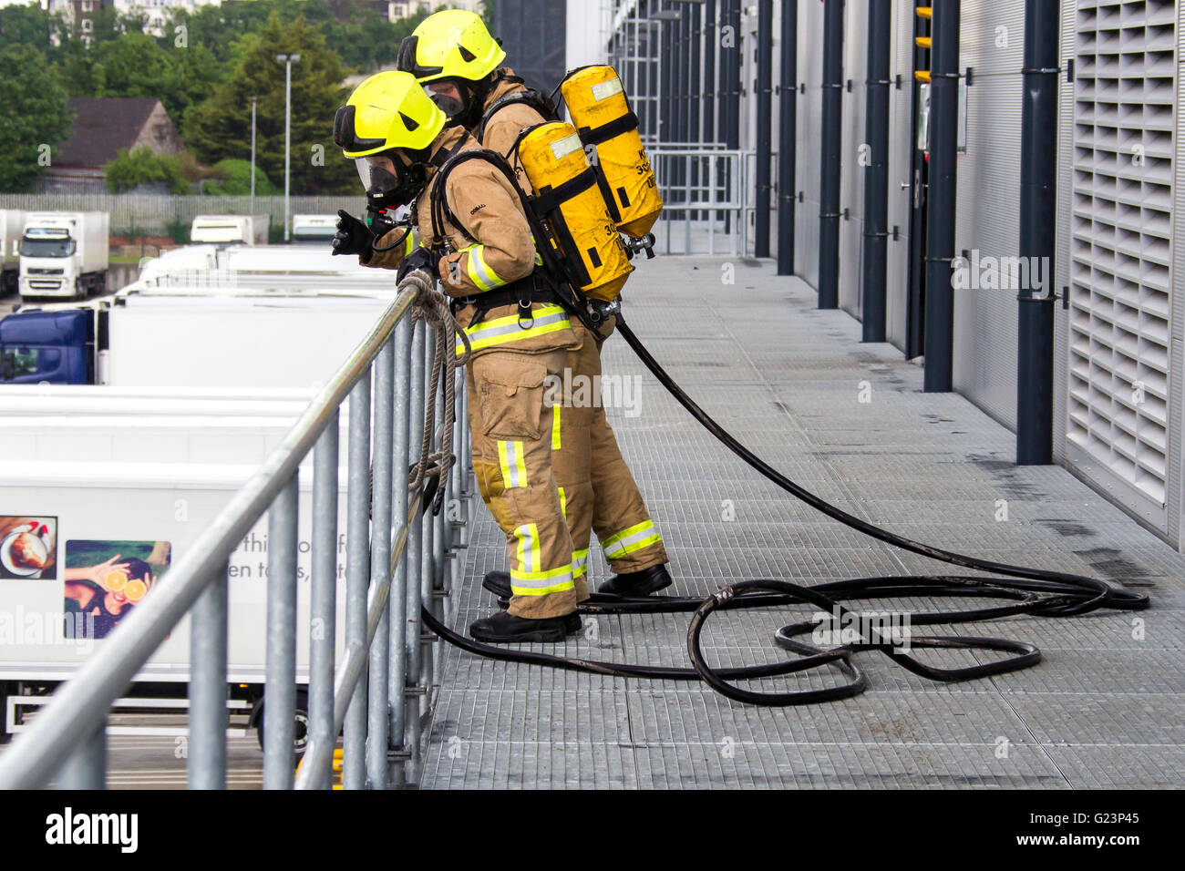 Firefighters wearing breathing apparatus drag a hosereel line on a ...