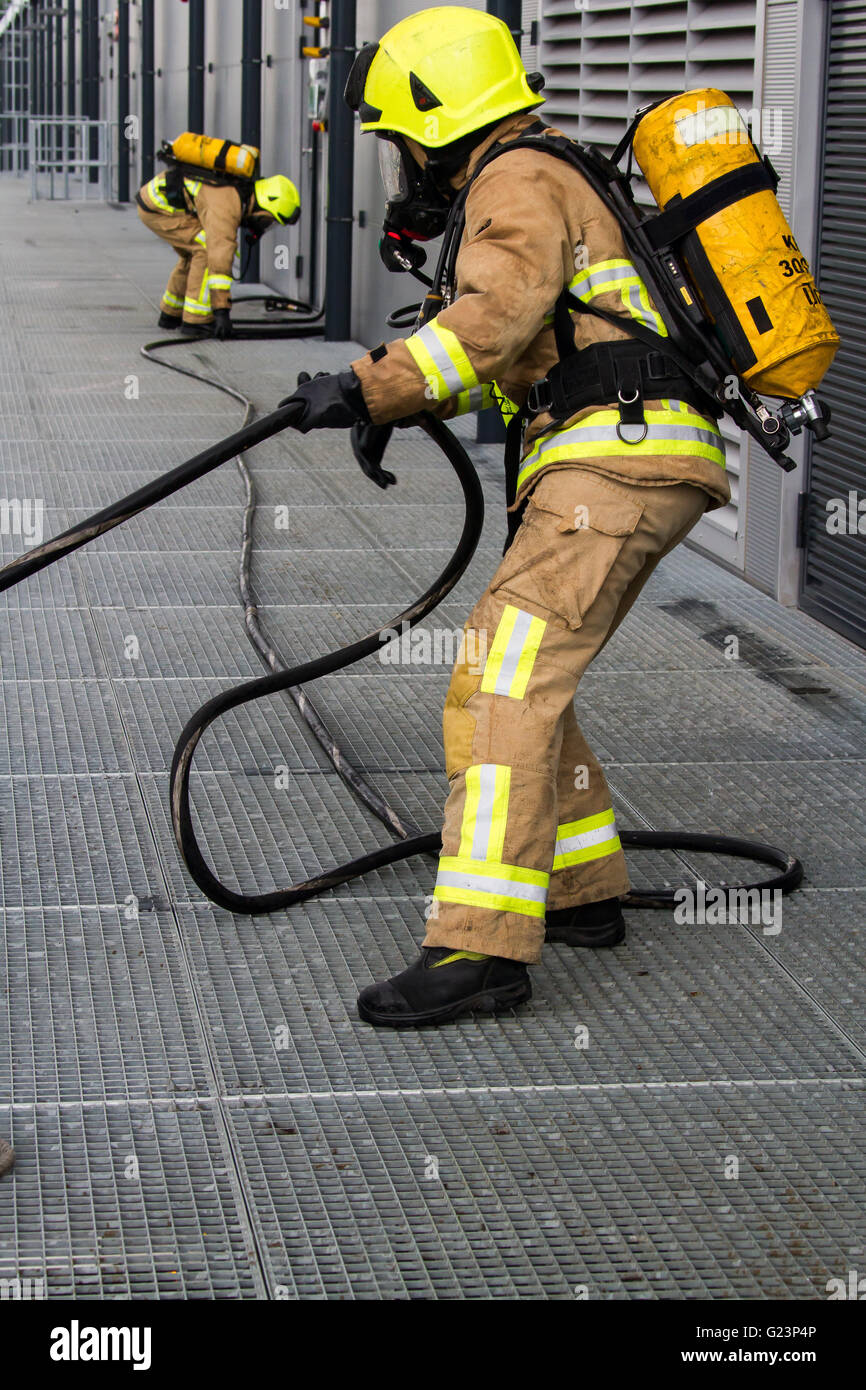 Firefighter wearing breathing apparatus drags a hosereel line on a ...