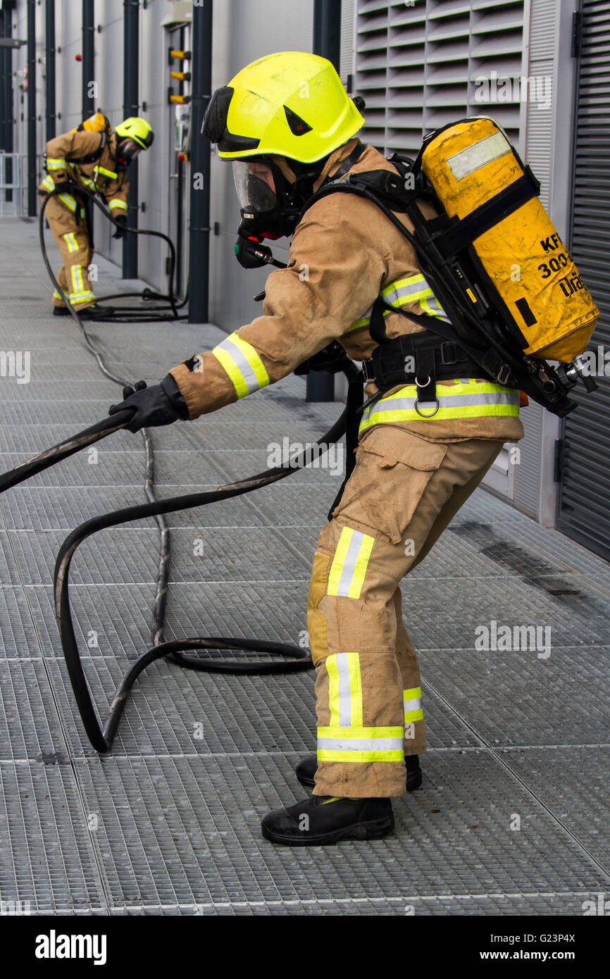 Firefighter wearing breathing apparatus drags a hosereel line on a ...