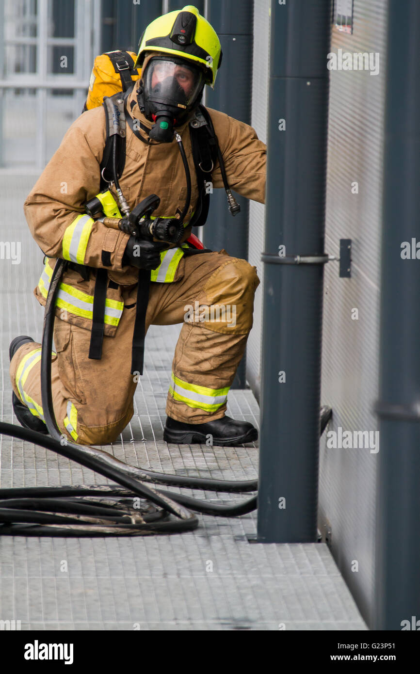 Firefighter wearing breathing apparatus with a hosereel jet prepares to ...