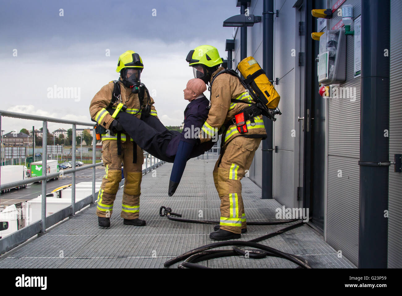 Firefighters wearing breathing apparatus carry a casualty dummy along a ...