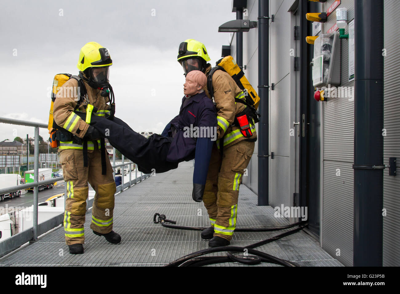 Firefighters wearing breathing apparatus carry a casualty dummy along a ...