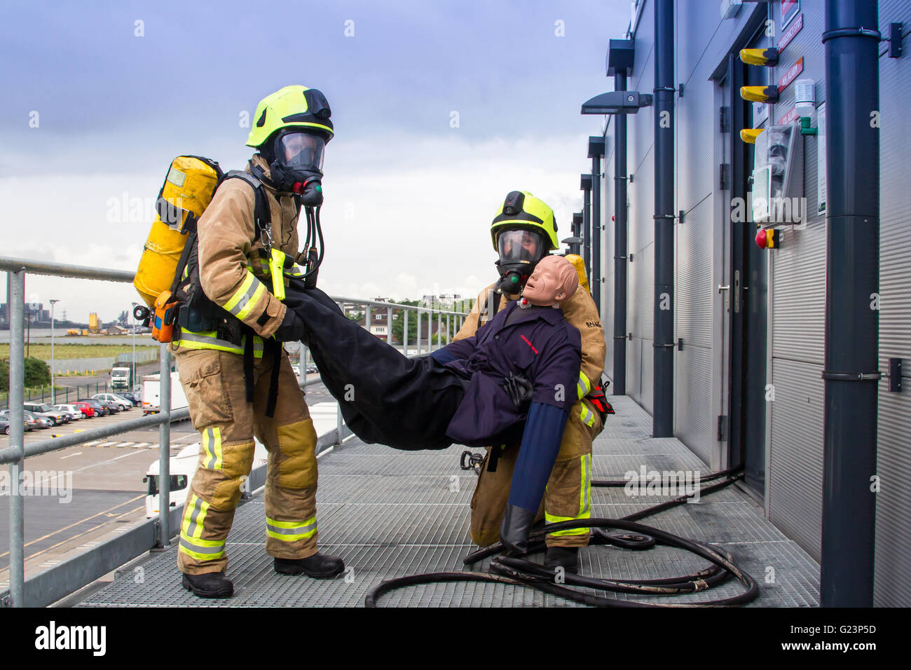 Firefighters wearing breathing apparatus carry a casualty dummy along a ...