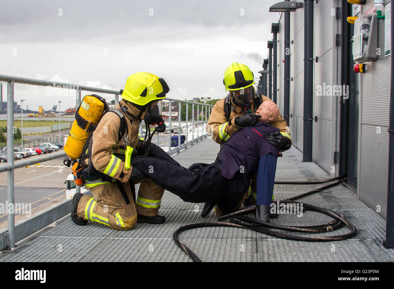 Firefighters wearing breathing apparatus carry a casualty dummy along a ...