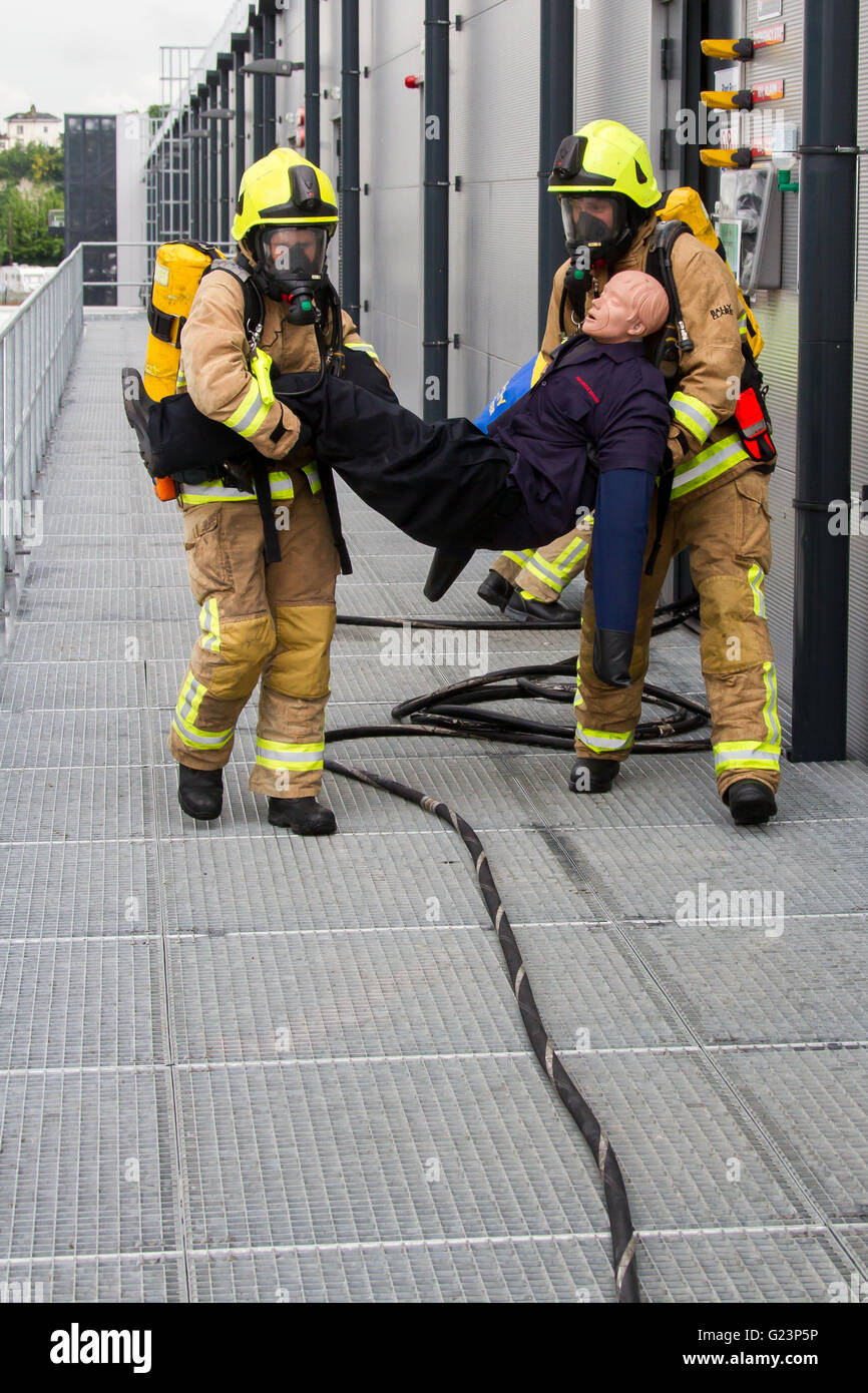Firefighters wearing breathing apparatus carry a casualty dummy along a ...