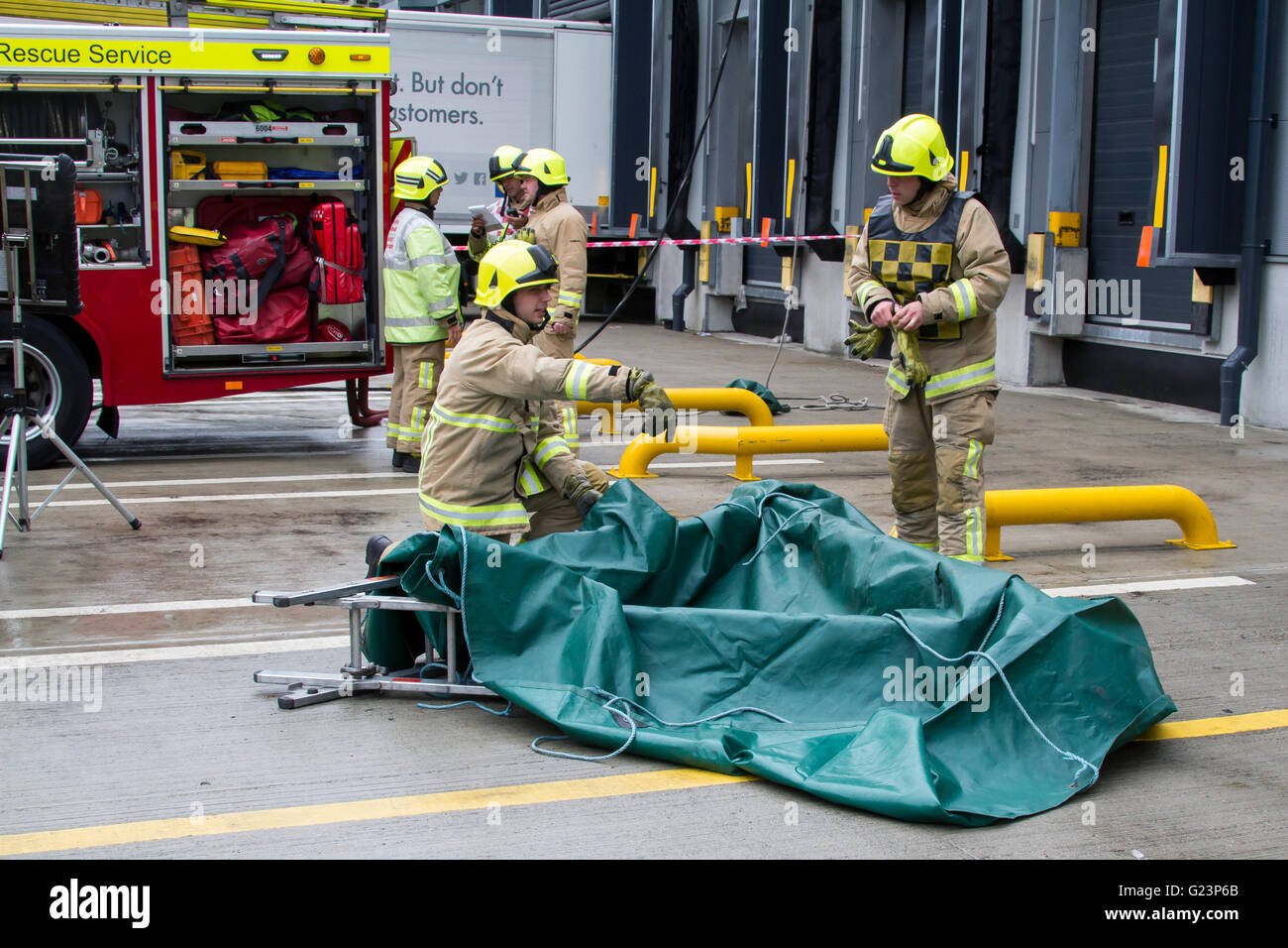 Fire fighters constructing a a dam using a salvage sheet and triple ...