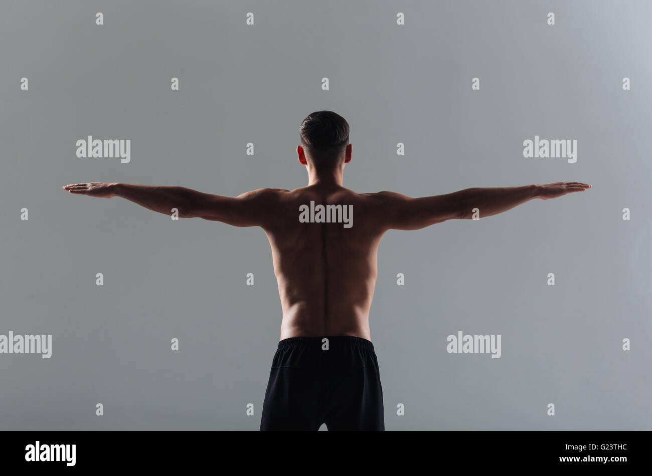 Back view portrait of a fitness man workout with arms at the sides over ...