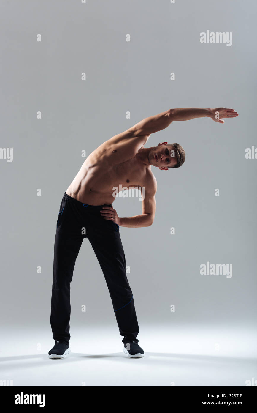 Full length portrait of a fitness man doing stretching exercises over ...